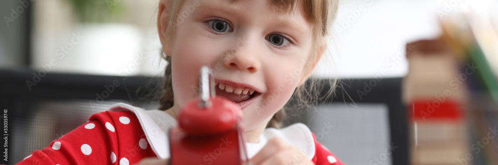 Portrait of involved little girl playing with alarm-clock. Cheerful ...