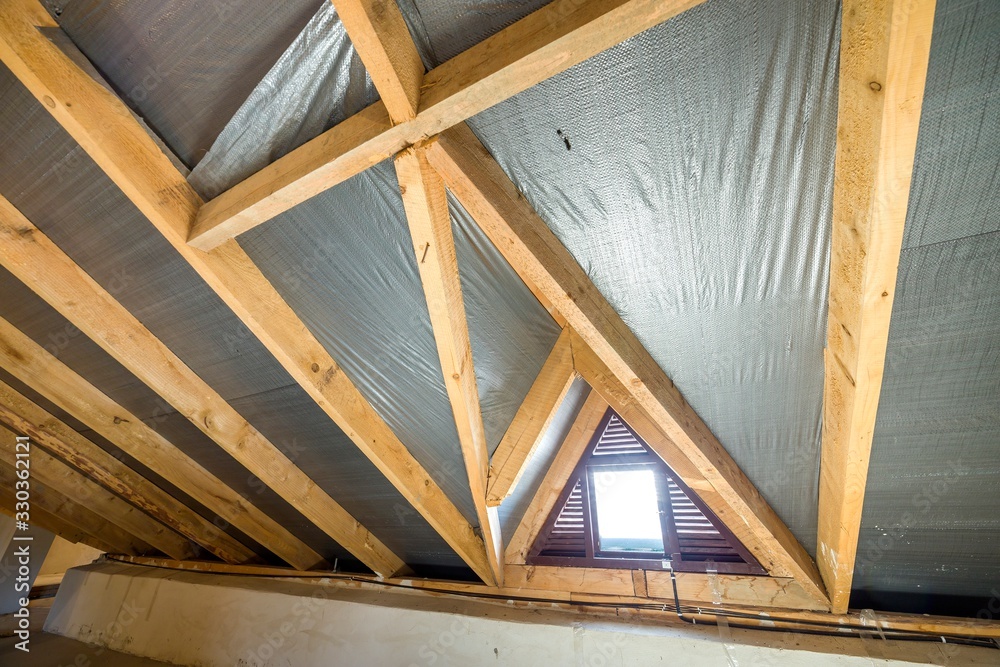 Attic of a building with wooden beams of a roof structure and a small ...