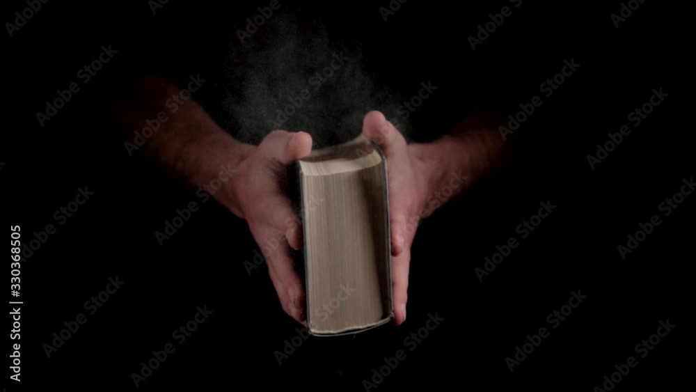 Slow Motion , hands holding and closing an old open book and dust is ...