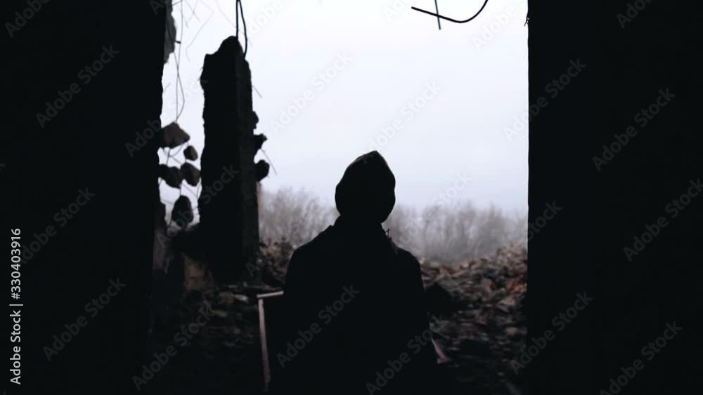 A boy enters a room in a bombed -out building. Before him are the ruins ...