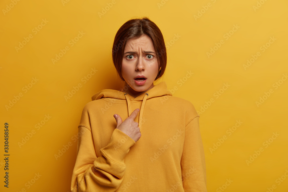 Perplexed indignant young woman points at herself, verbally defenses ...
