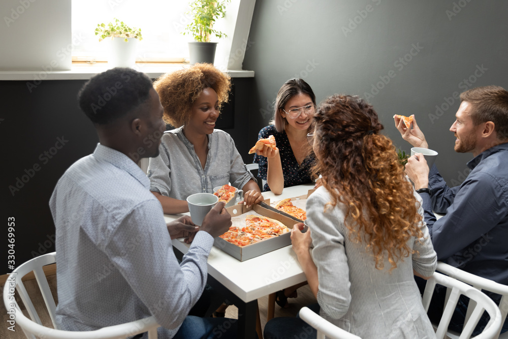 Excited diverse employees team eating pizza at lunch break, having fun ...