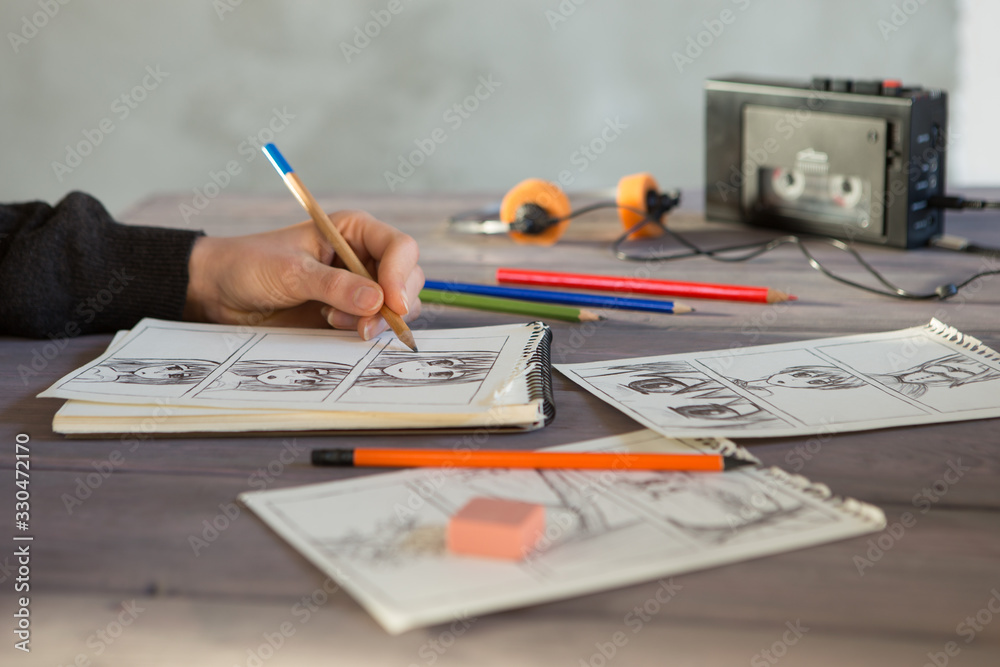 Artist drawing an anime comic book in a studio. Wooden desk, natural ...