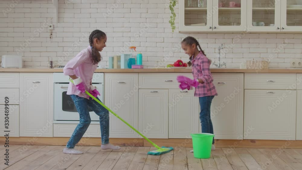 Positive carefree little african american sisters doing household ...