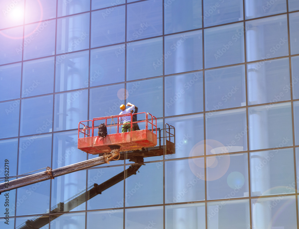 Working window cleaner on a telescopic platform washes the Windows of a ...