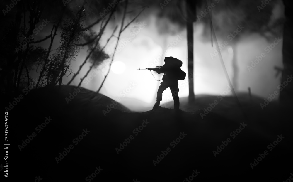 Army sniper with large caliber rifle standing in the fire and smoke ...