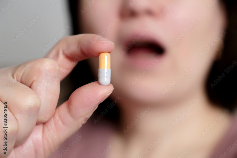 Woman takes a pill, girl putting capsule in open mouth. Sick female ...