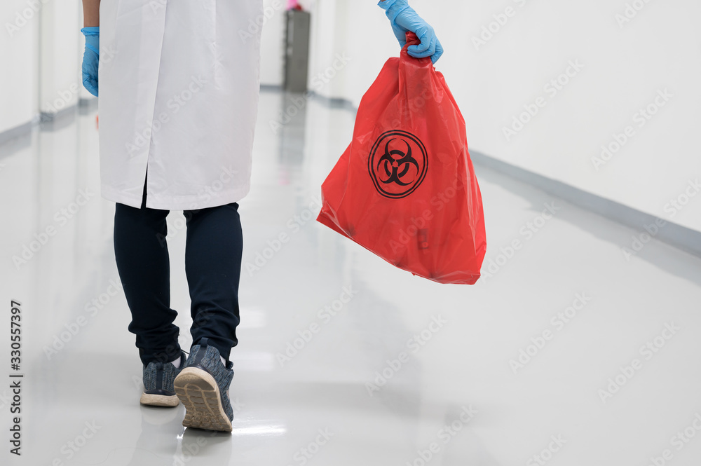 Scientist wearing blue gloves and red bag with bioharzard sign.A woman ...