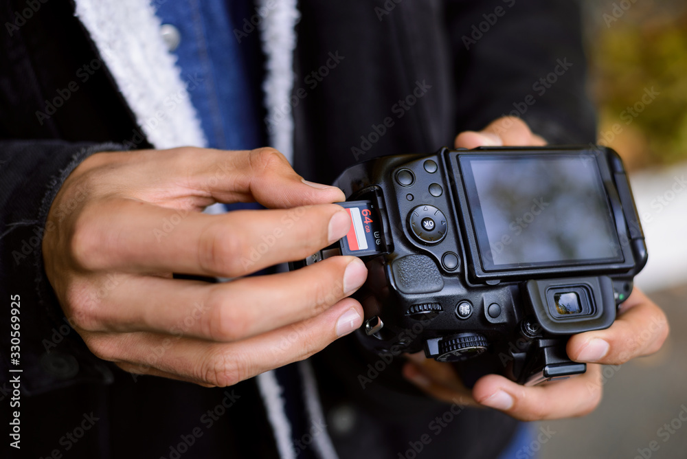 Photographer hand holds Memory card - Flash card near professional DSLR ...