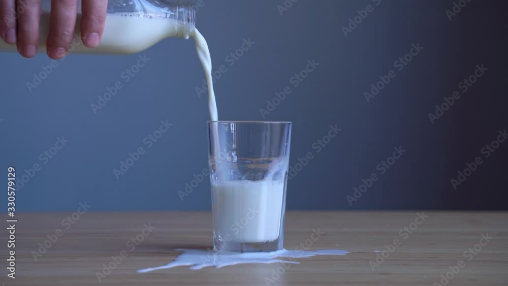 front view closeup of Caucasian male hand pouring milk from a bottle ...