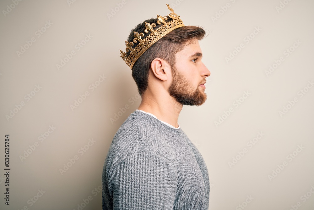 Young blond man with beard and blue eyes wearing golden crown of king ...