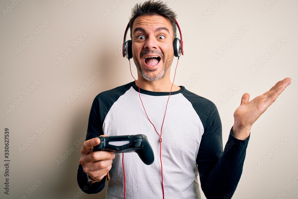 Young handsome gamer man playing video game using joystick and ...