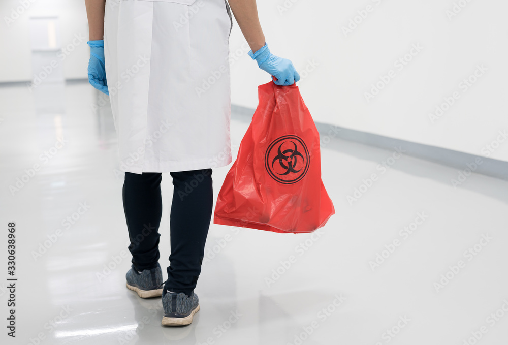 Scientist wearing blue gloves and red bag with bioharzard sign.A woman ...