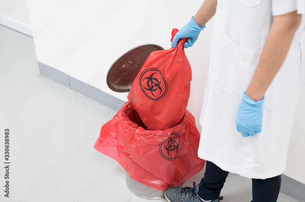 Scientist wearing blue gloves and red bag with bioharzard sign.A woman ...