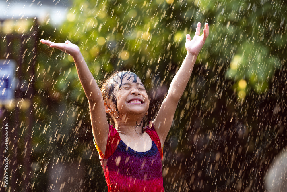 Asian children playing in the rain are happy. Stock Photo | Adobe Stock