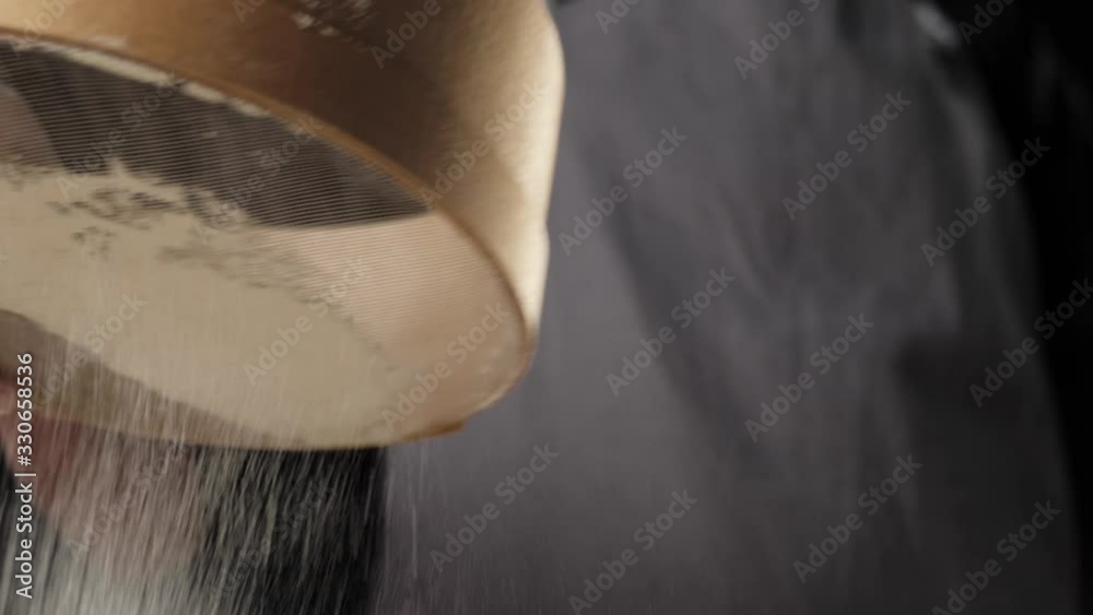 Professional baker hands sift flour through a wooden sieve on the table ...