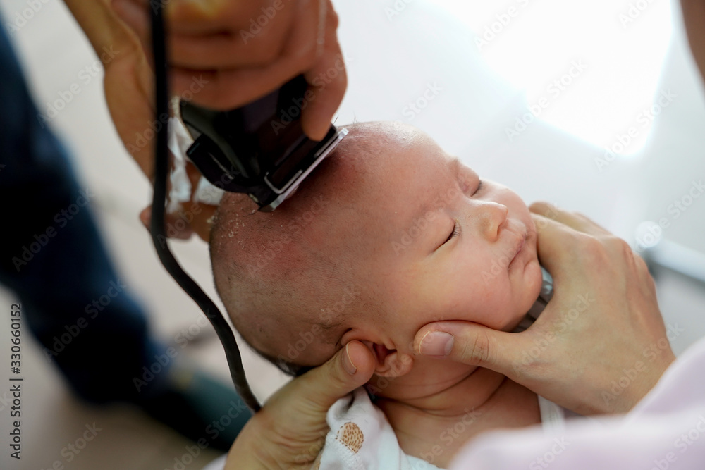 Baby one month old is shaved the hair in barber shop. Thai traditional ...
