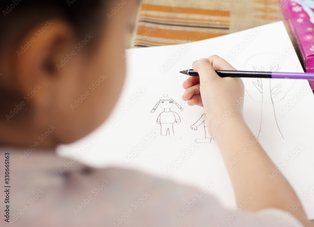 cropped view of little girl drawing a woman on a paper with a pencil ...