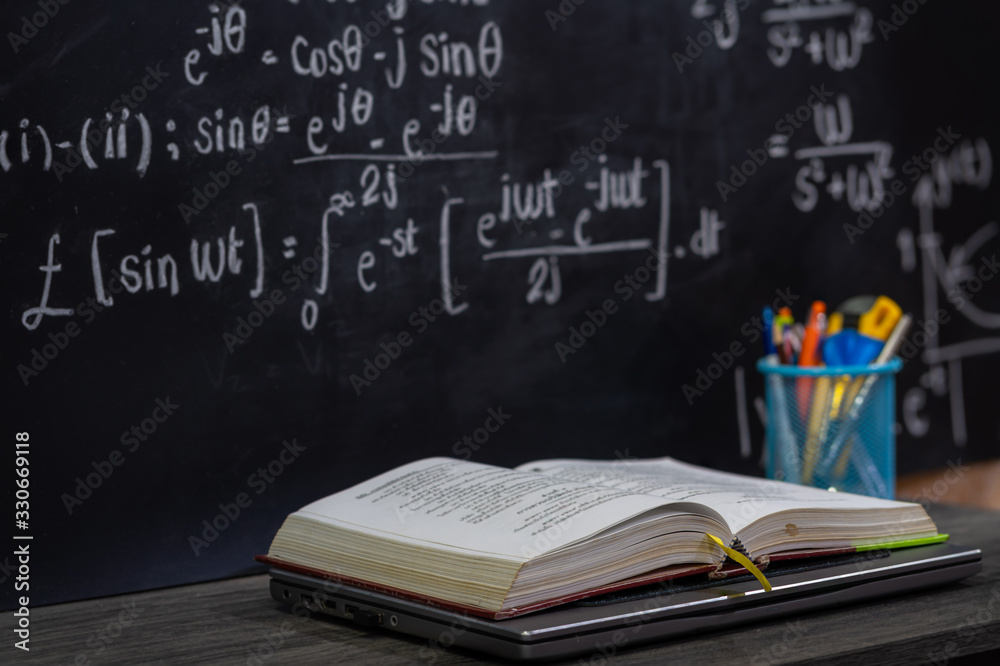 Open book on the table in classroom with blackboard background, back to ...