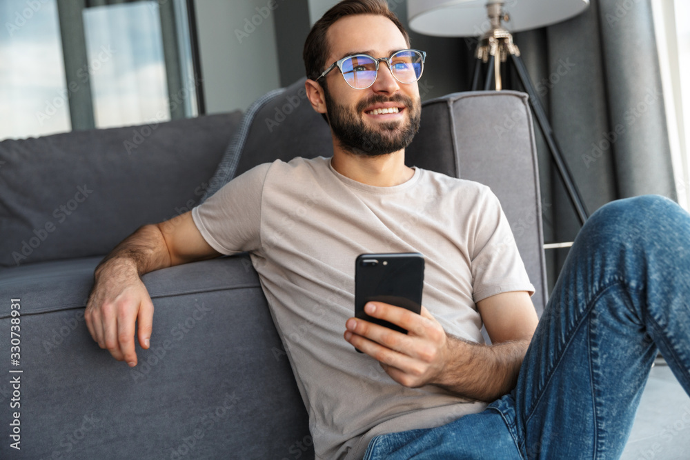 Attractive smart young man sitting on a floor in the living room Stock ...