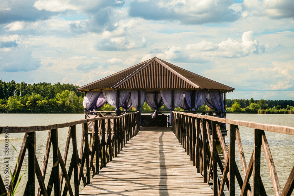 Wooden gazebo on the quet lake. Cloudy scape with over water ...