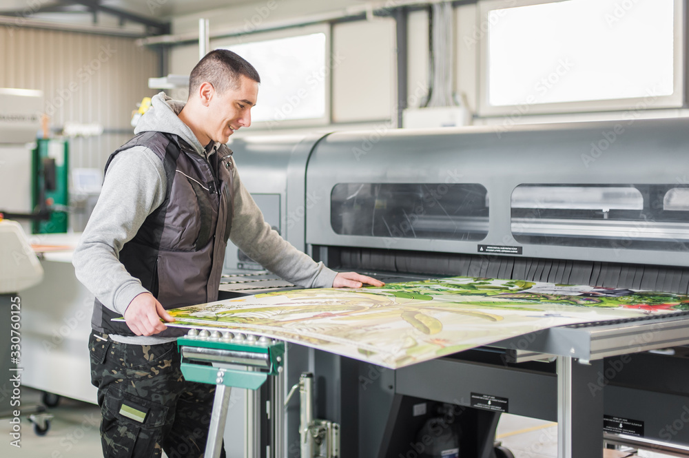 Technician operator works on large premium industrial printer plotter ...