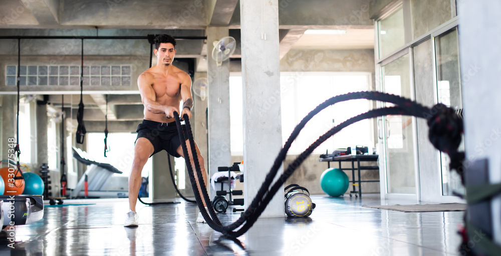 Sports man with battle rope battle ropes exercise in the fitness gym ...