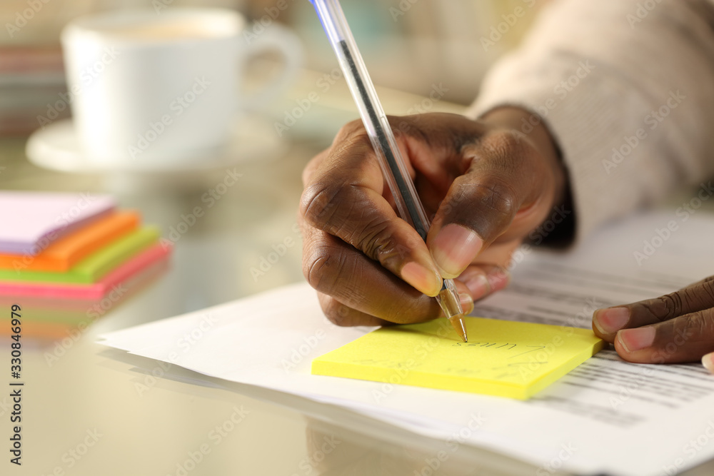 Black man hand writing on sticky note on a desk Stock Photo | Adobe Stock