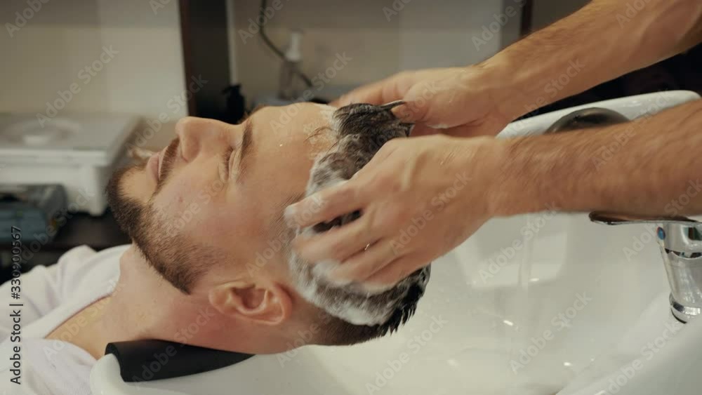 Close up view of hairstylist washing head of client with shampoo ...