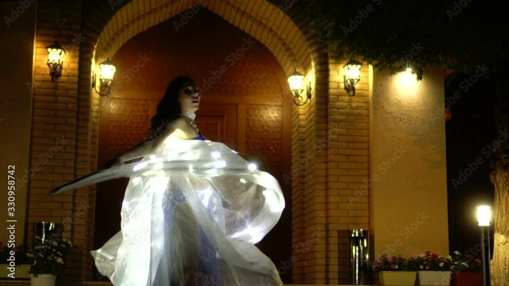 Belly dancer girl dance with two glowing lights wings. Colorful belly ...