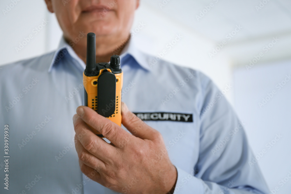 Professional security guard with portable radio set indoors, closeup ...