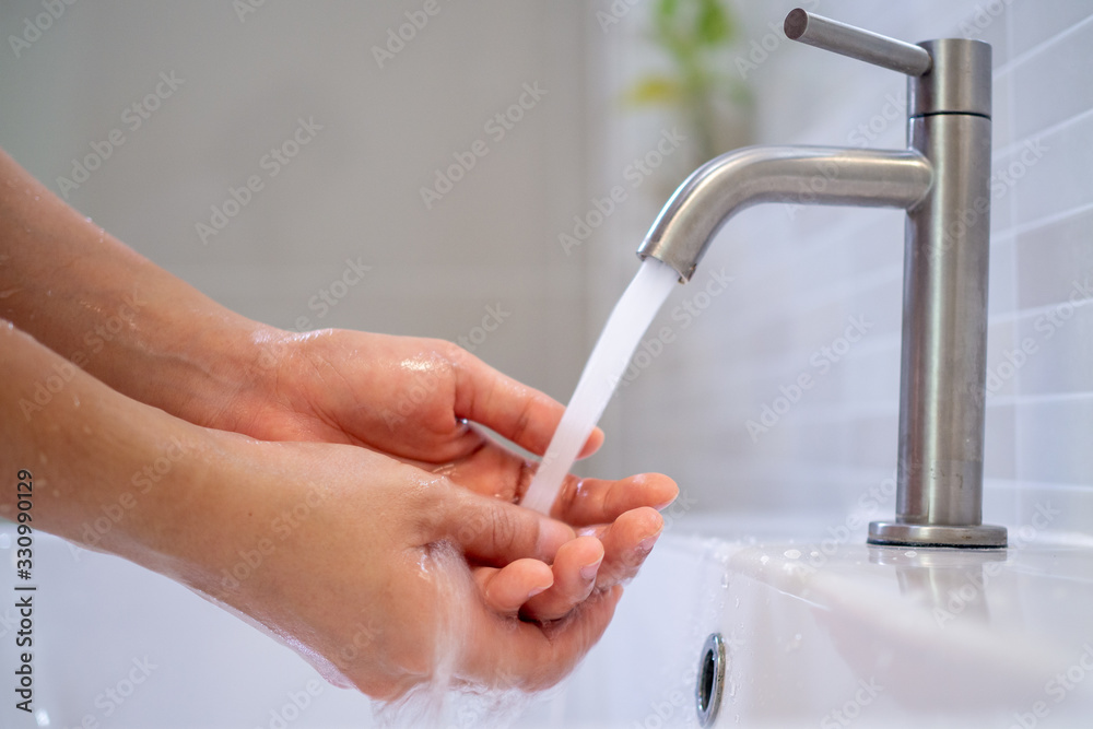 Women turn on the water to wash their hands in the bathroom. Frequent ...