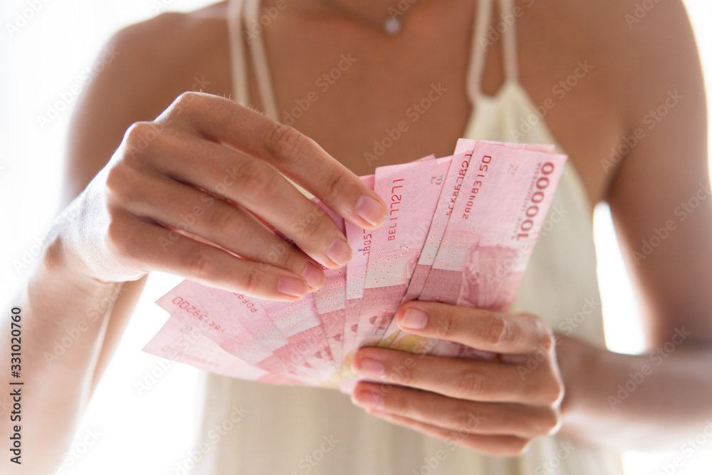Foto De Girl Recounts Denominations Of 100 Thousand Indonesian Rupees foto-de-girl-recounts-denominations-of-100-thousand-indonesian-rupees