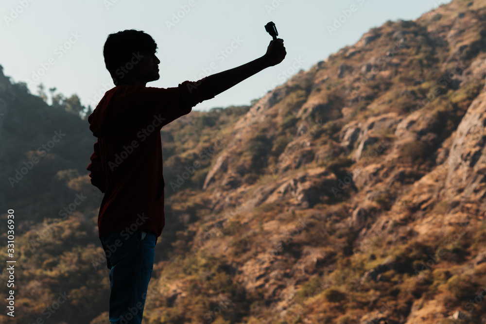 Indian man holding action camera in front of him in front of Mountain ...