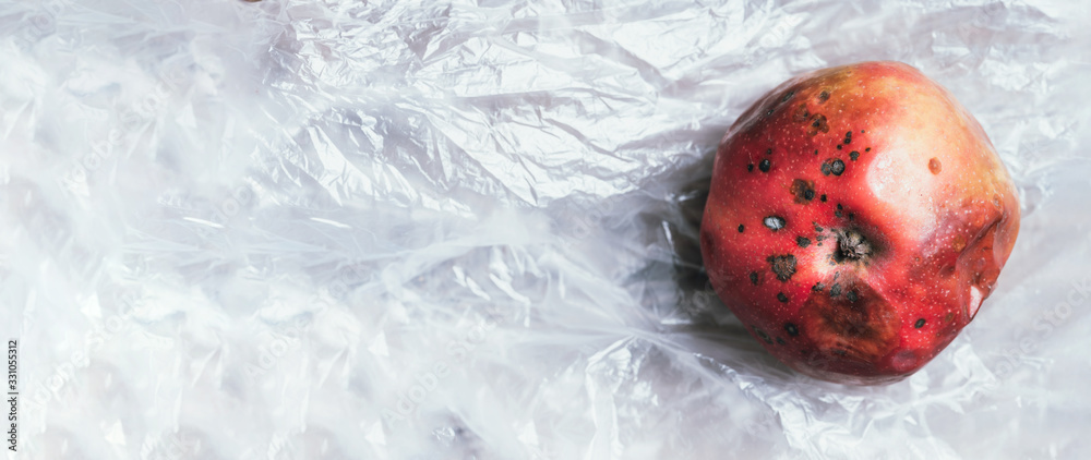 Spoiled bad red apple on plastic bag background. Garbage dump rotten ...