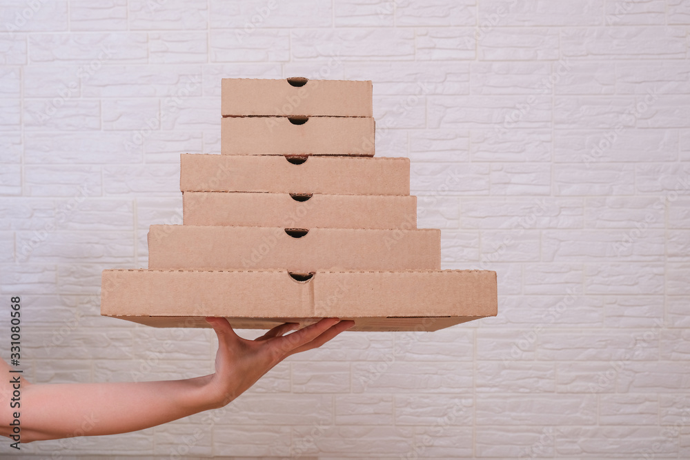 Hand holding many stacked carton pizza boxes of different sizes ...