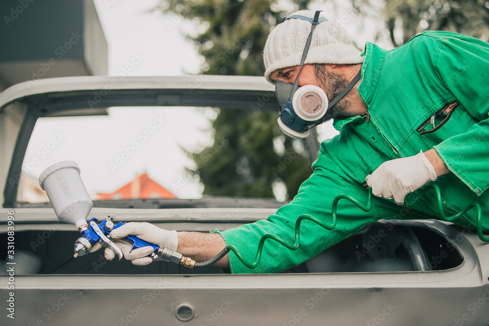 Caucasian man is spraying color with a compressed air paint gun on the ...