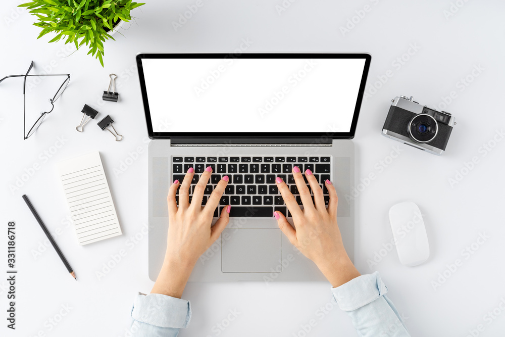 Elegant workspace. Young woman’s hands using laptop with blank display ...