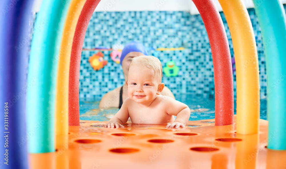 Cute little boy is lying on his belly on a floating colorful ...
