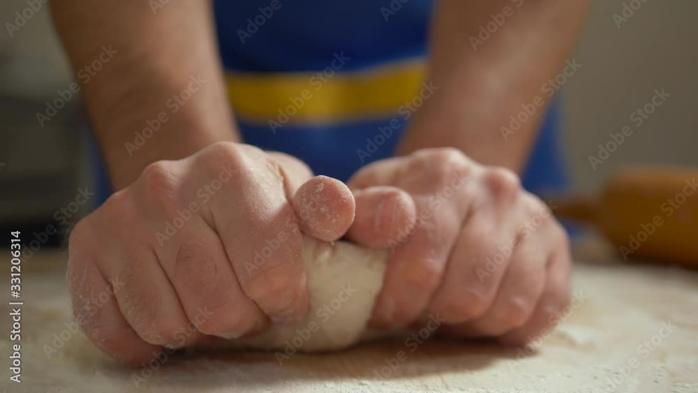 SHALLOW DEPH: Male hands kneading dough in flour on the table. Close up ...