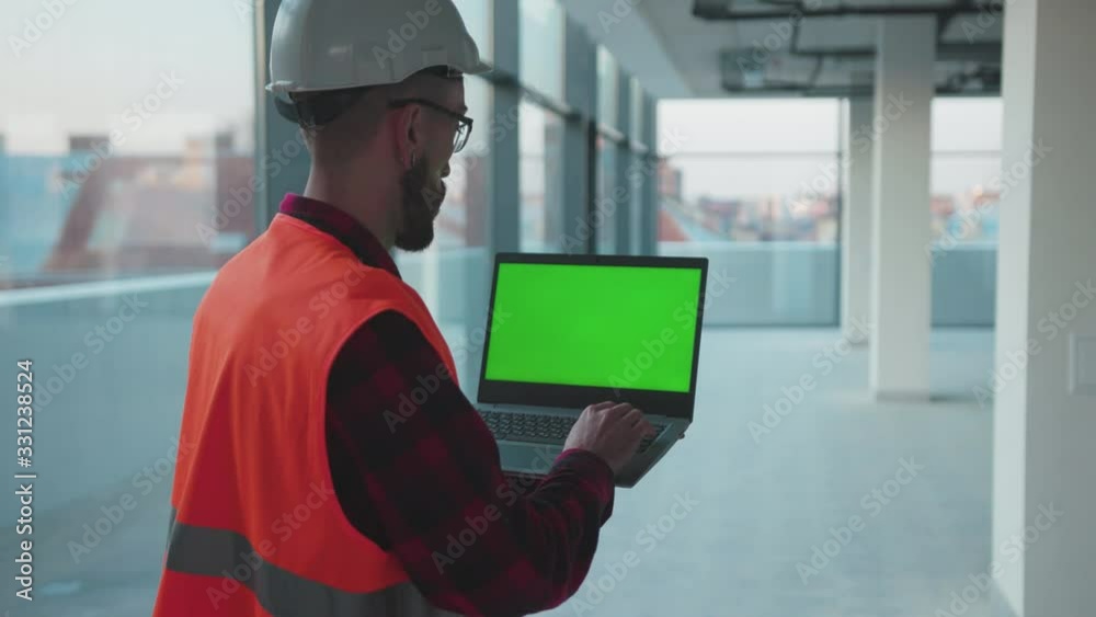 Inside in building man engineer stand using laptop computer with green ...