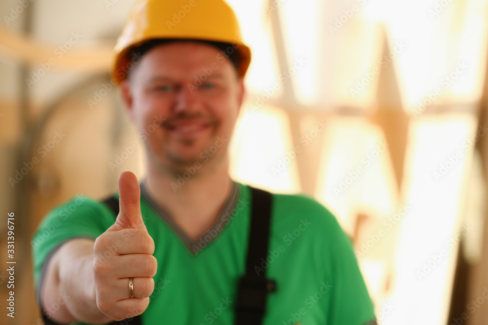 Smiling worker in yellow helmet show confirm sign with thumb up at arm ...