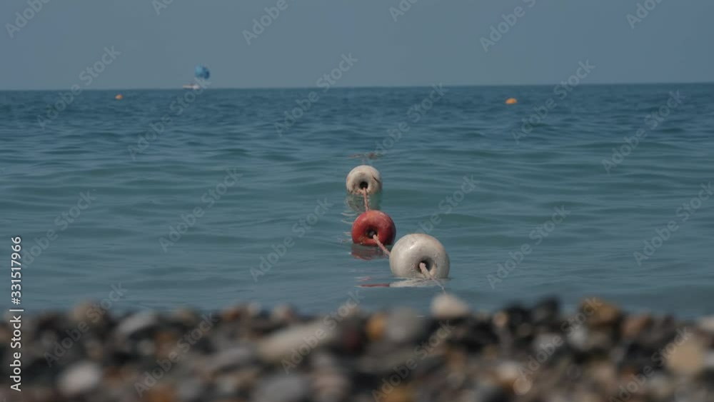 A line of floating red and white buoys lying on the surface of the ...