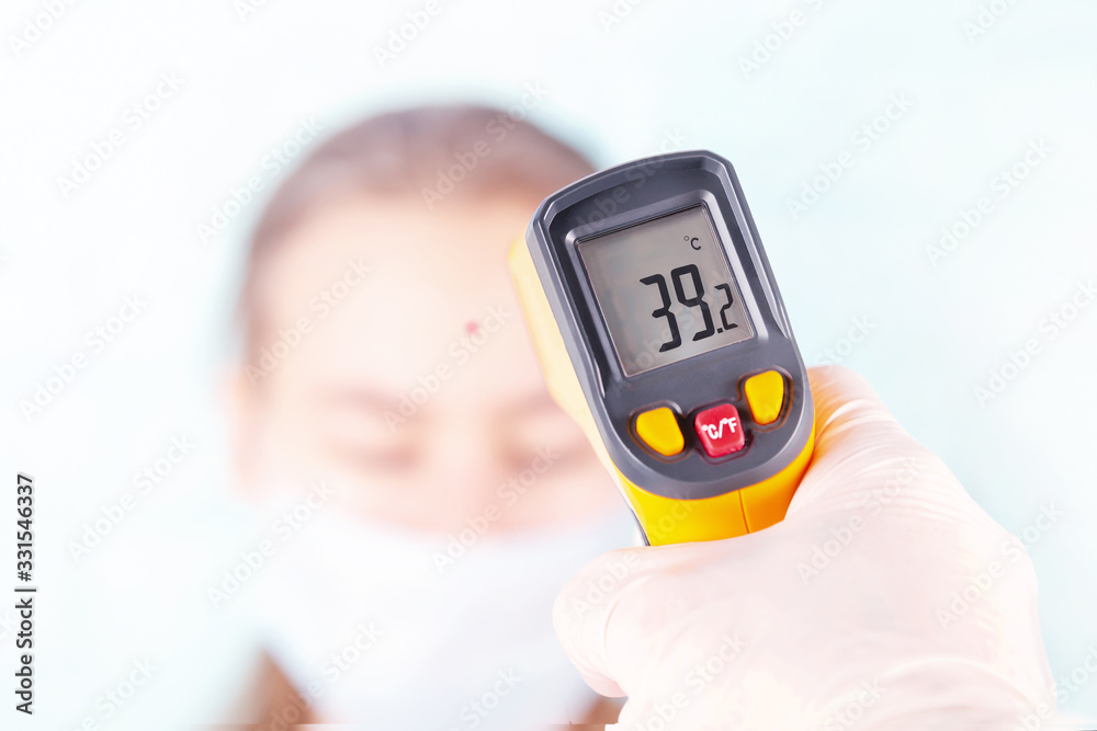 Scanner showing fever temperature to a masked man. Hand in a medical ...