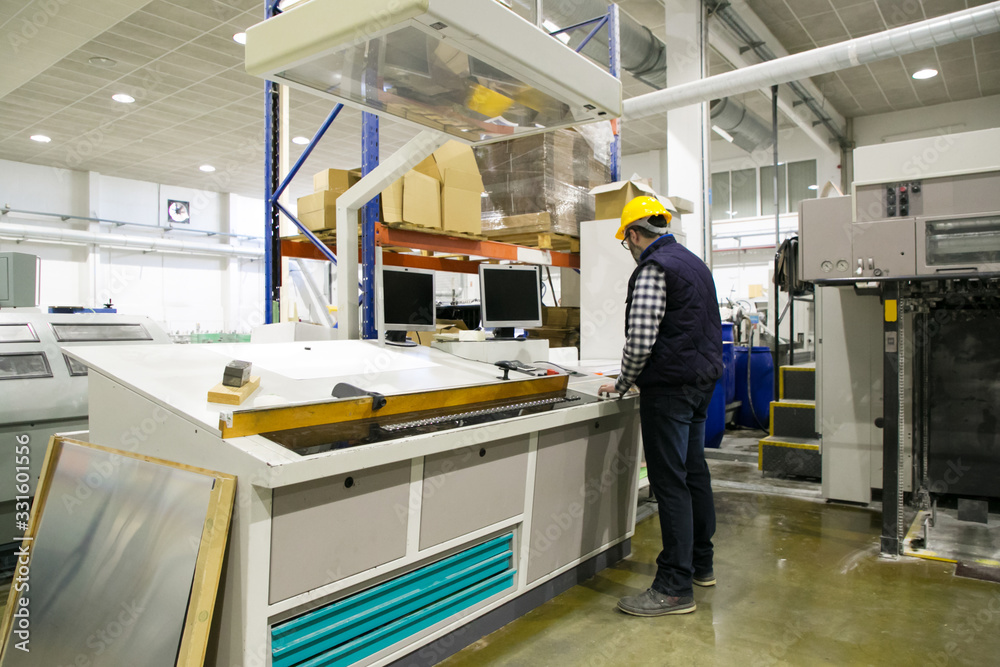 Foto de Back of male technician operating milling machine at control ...