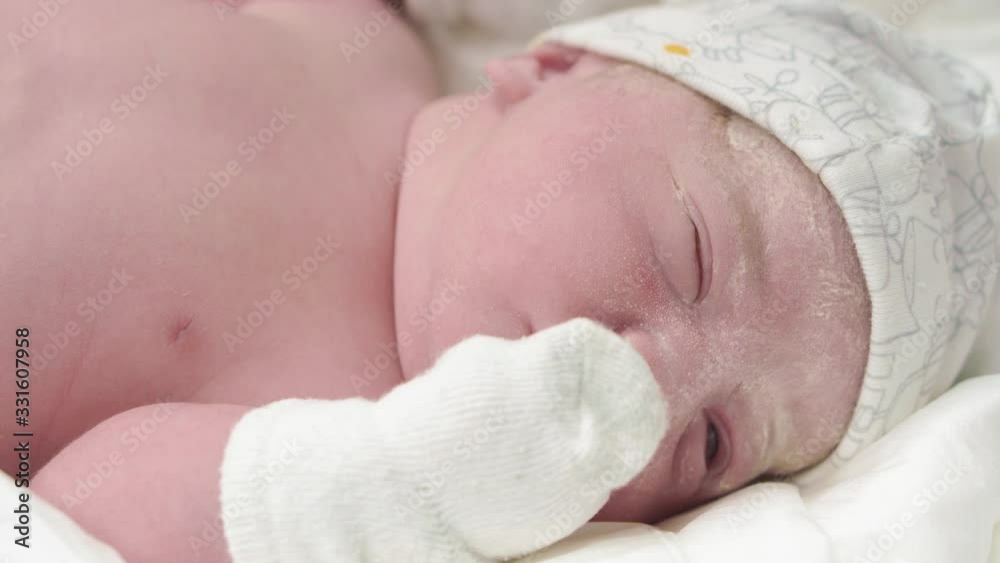 A close-up portrait of a crying newborn in a primordial grease that ...