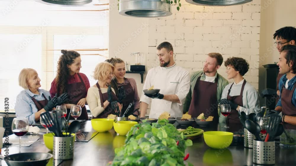 Group of guys and girls are clapping hands to chef holding cooked dish ...