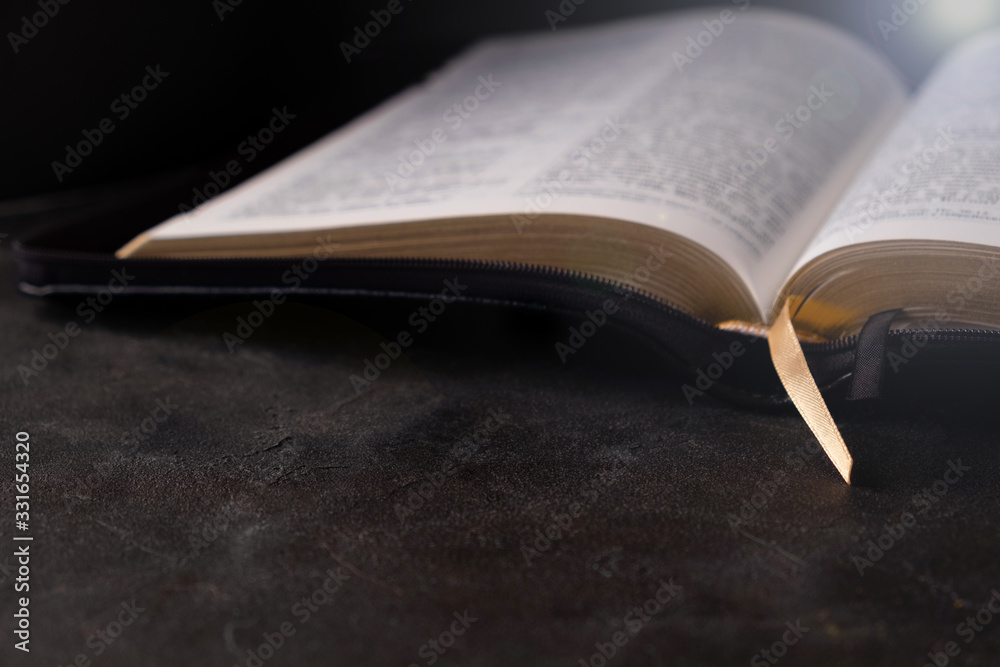 Open Bible on a dark table with light coming from above. Christianity ...