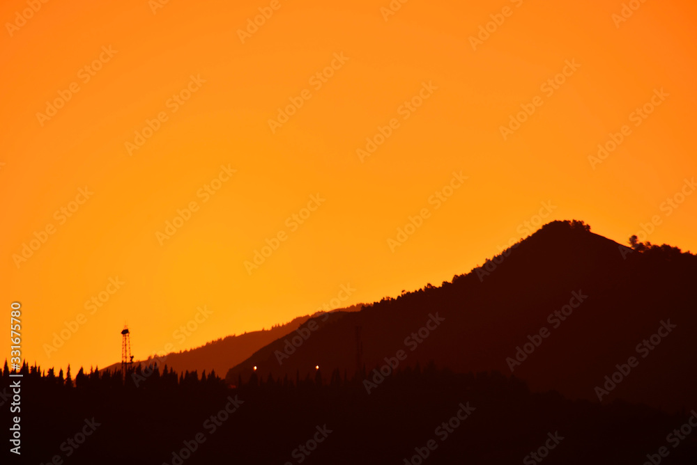 Silueta de un monte y una torre sobre un cielo anaranjado Stock Photo ...