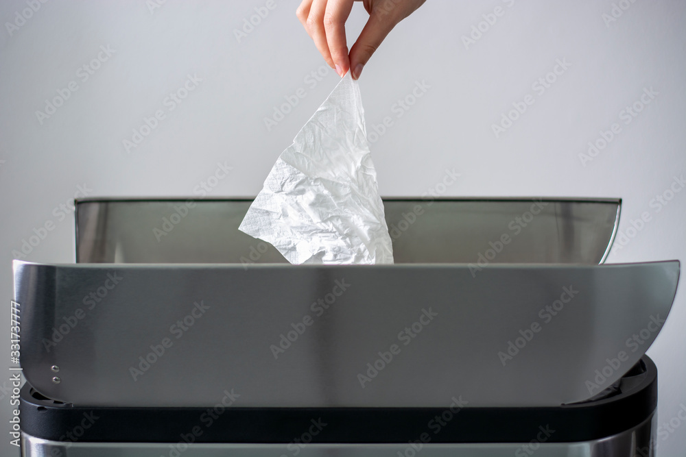 Women hand throwing a white used crumpled tissue paper into a garbage ...